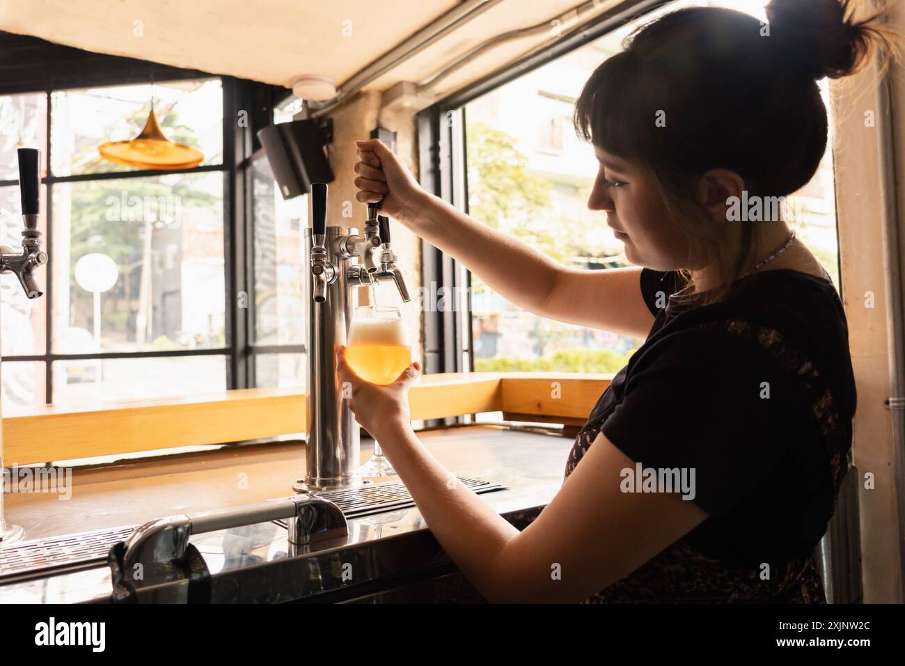 Profile silhouette of a woman serving draft beer in a bar with large ...