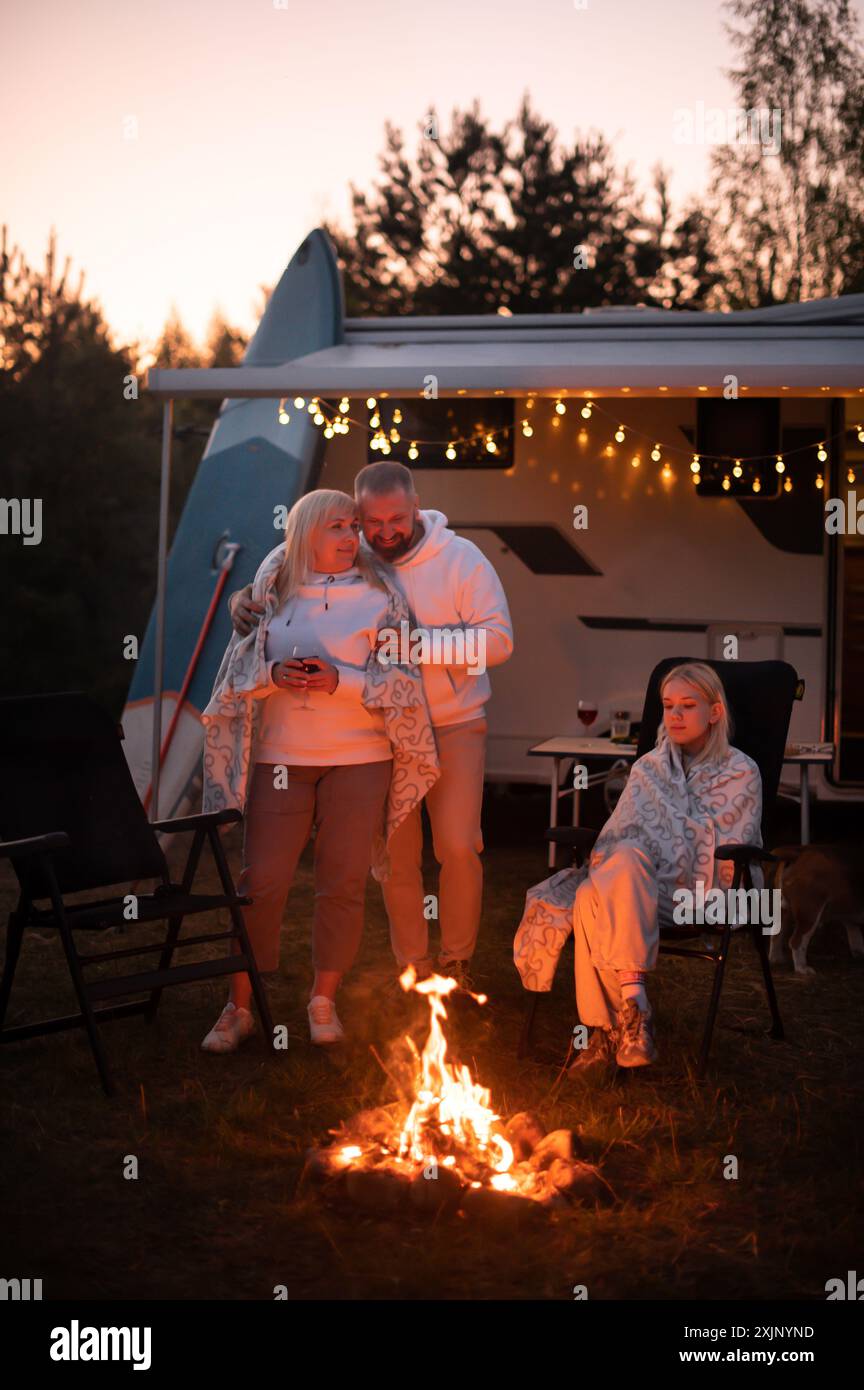 The family is relaxing together by the campfire near their mobile home ...