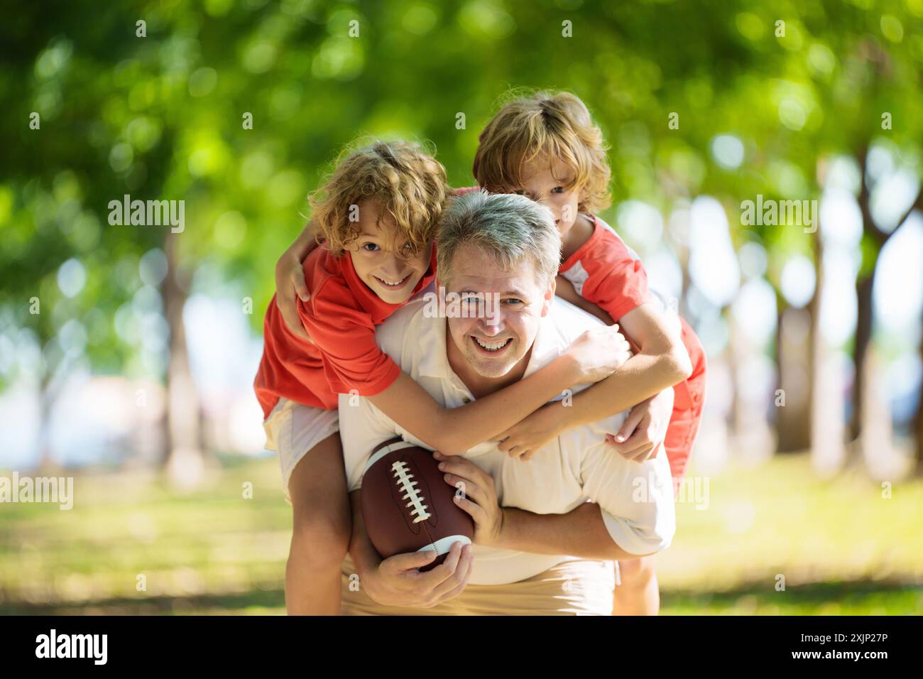 Family playing American football. Kids play rugby in sunny summer park ...