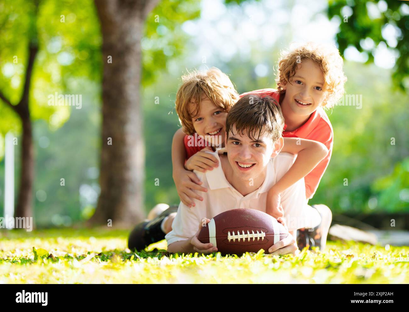 Family playing American football. Kids play rugby in sunny summer park ...