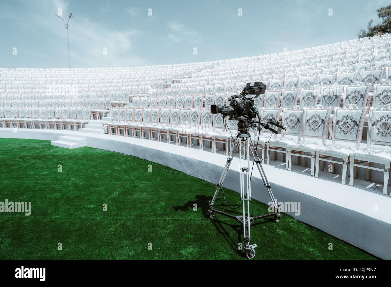 A professional video camera on a tripod set up in an empty outdoor ...