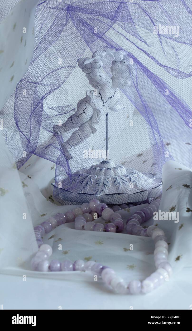 Loving cupid on petal pedestal surrounded with purple fabric netting ...