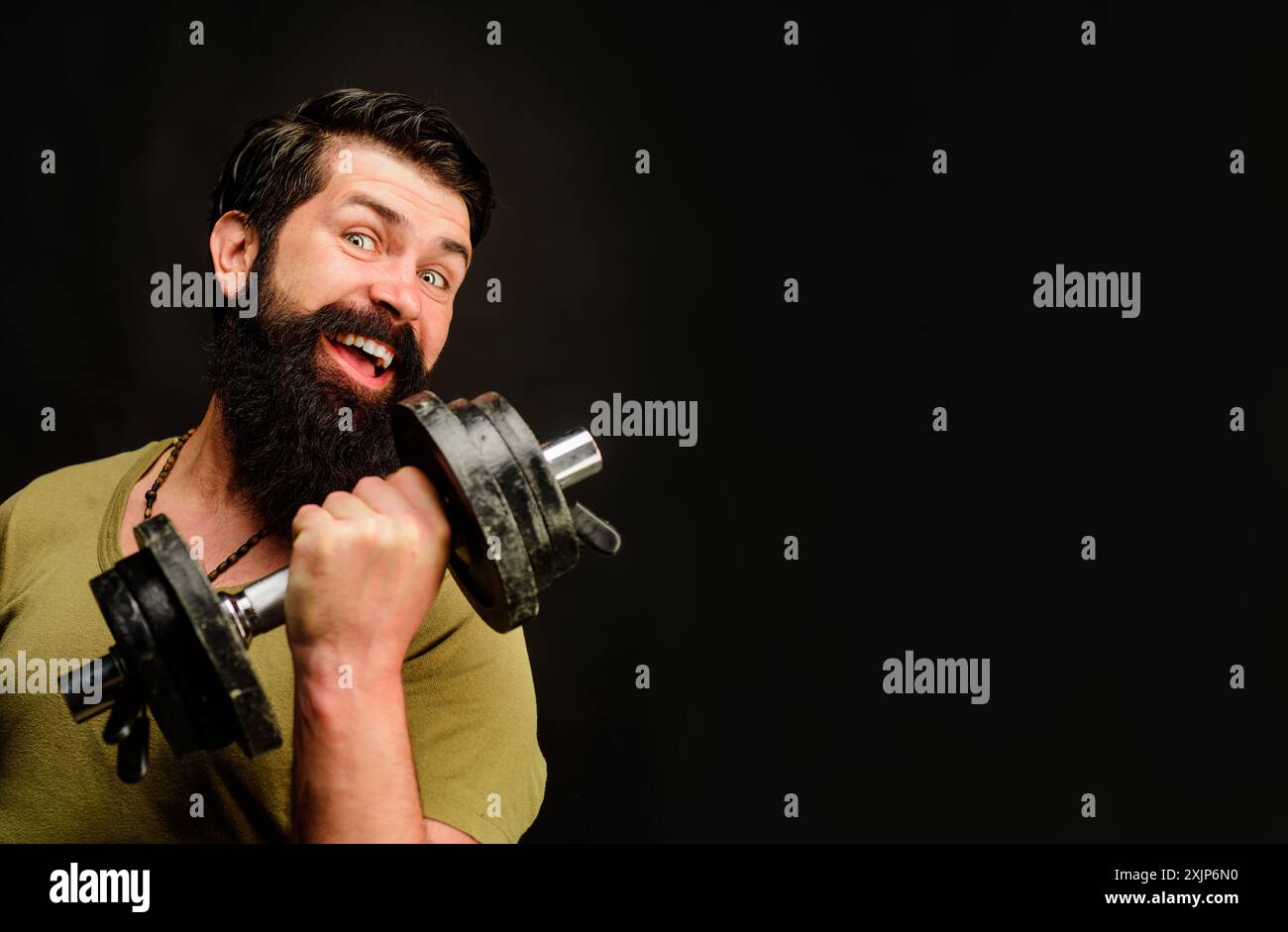Bearded bodybuilder man athlete doing workout with dumbbells. Strong handsome male fitness model ...