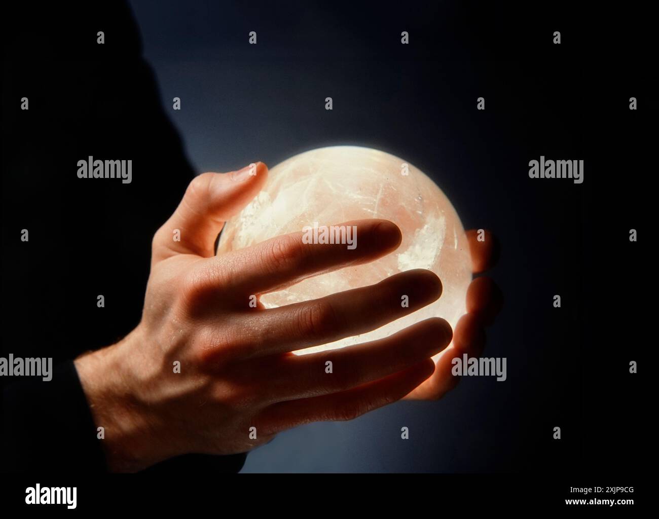 A person is holding a large, luminous crystal ball in their hands. The ...