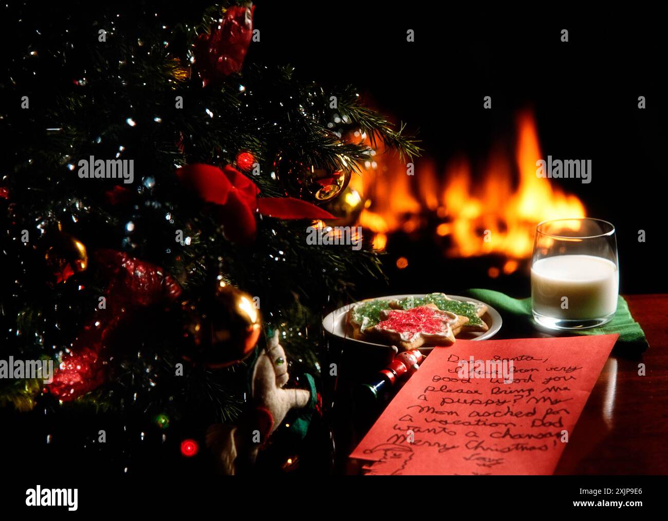 A decorated Christmas tree is positioned beside a roaring fireplace. A ...