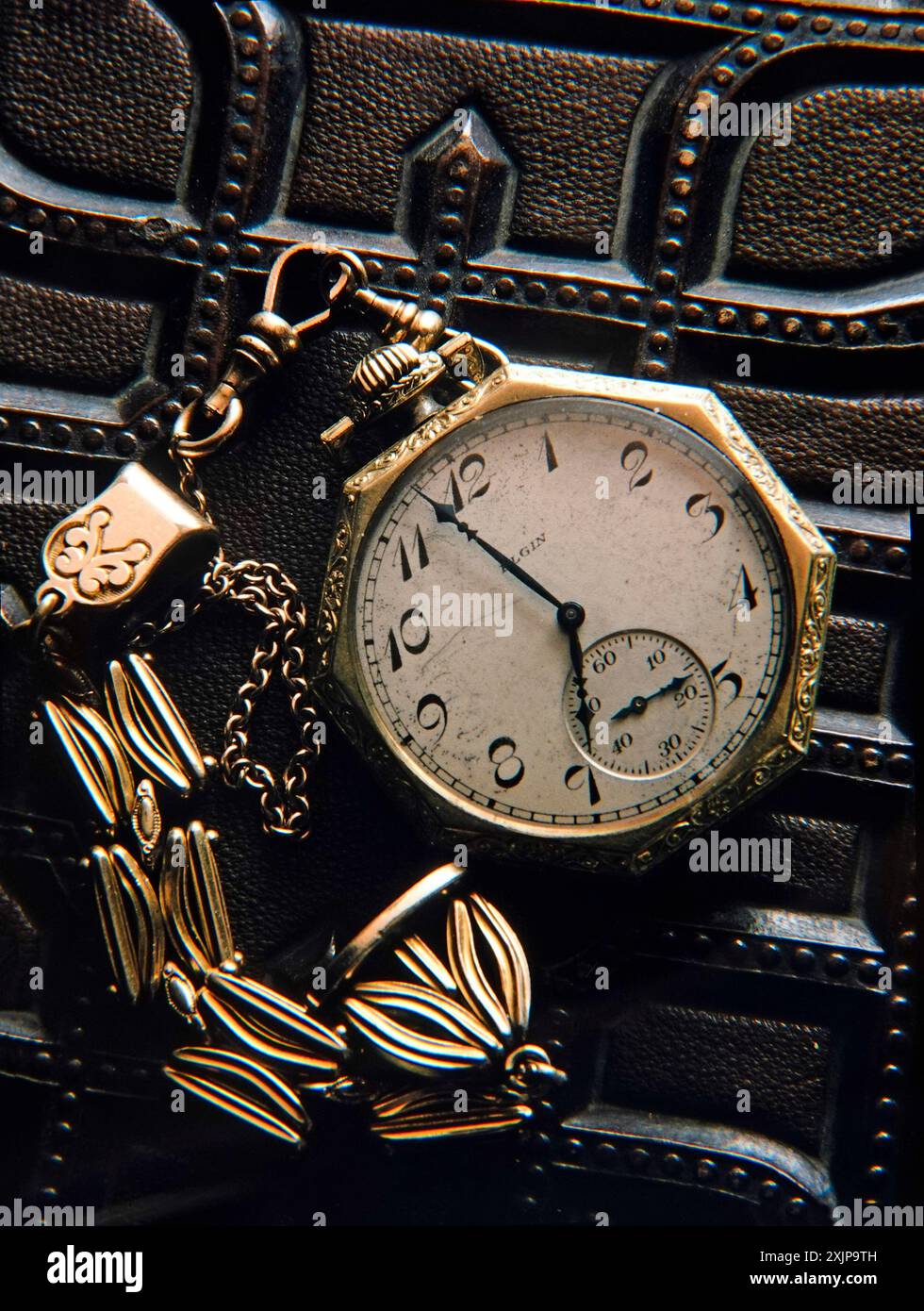A vintage gold pocket watch with a delicate chain lies on a richly ...