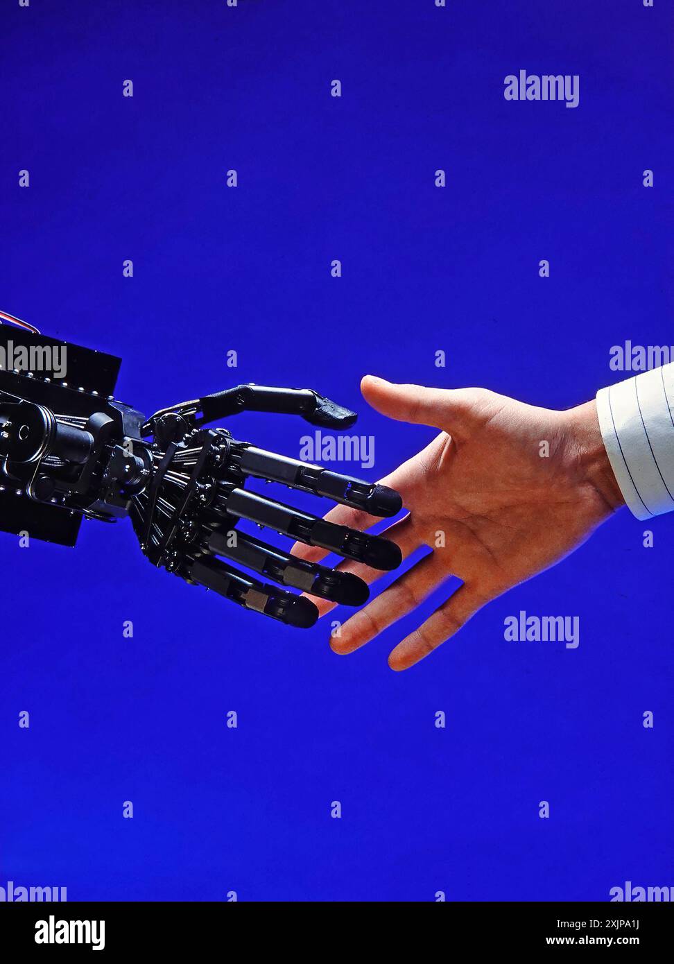 A robotic hand extends towards a human hand, both reaching out in a gesture of connection and ...