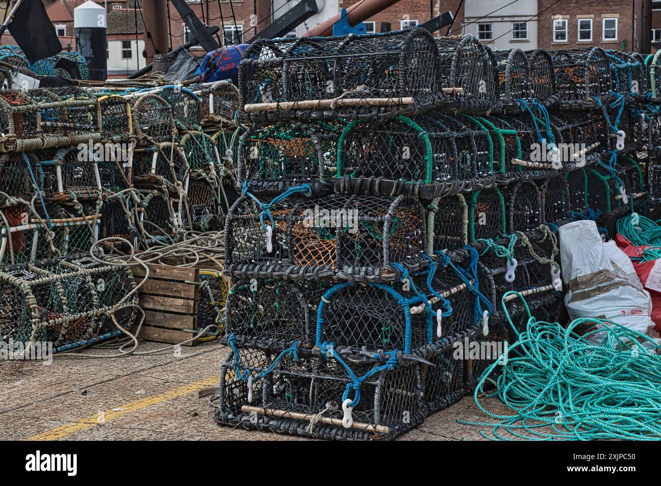A stack of lobster traps with ropes and buoys on a dock, ready for use ...