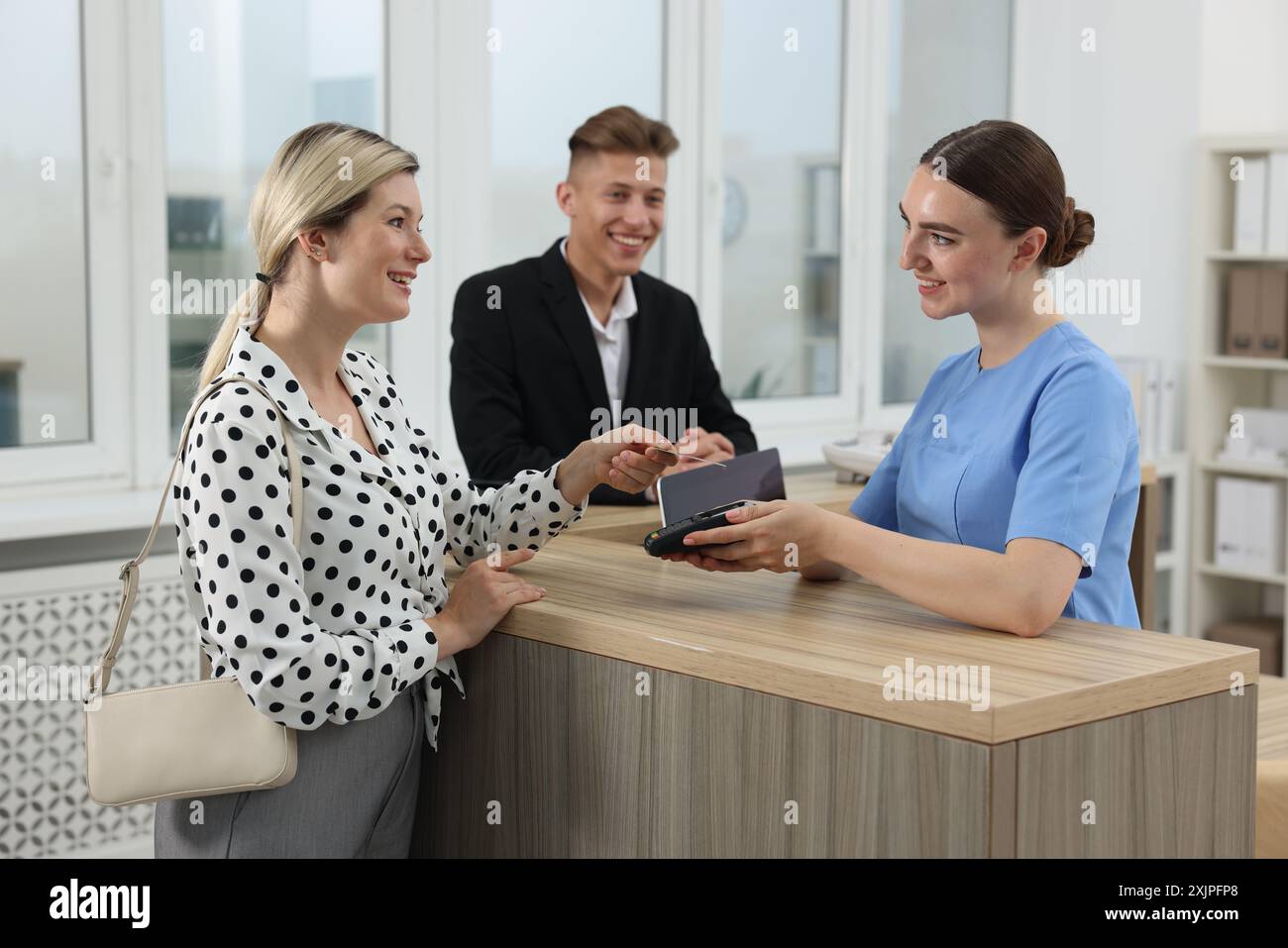 Receptionist taking payment from client via terminal at hospital Stock ...