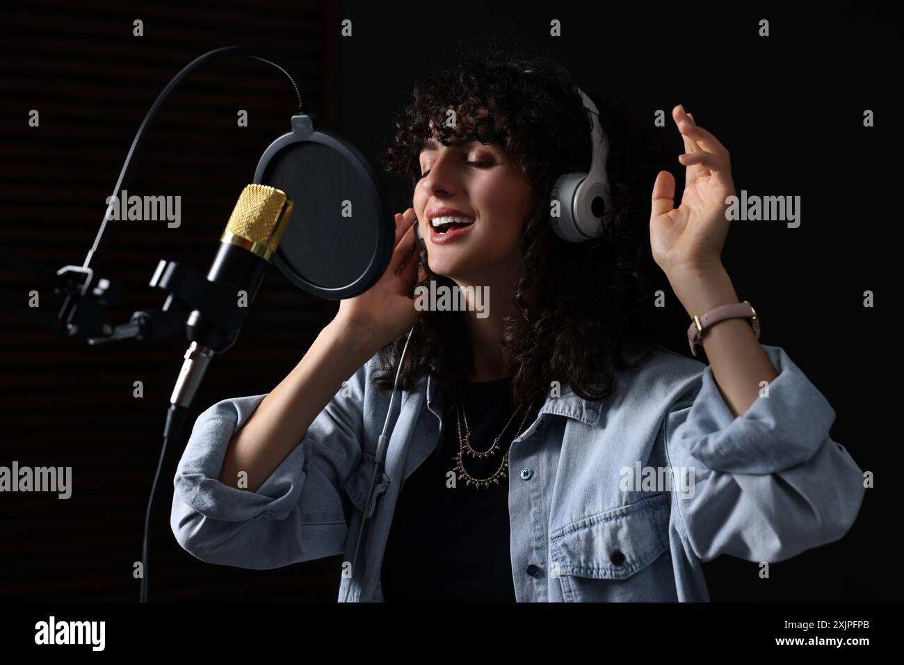 Vocalist with headphones singing into microphone in professional record ...