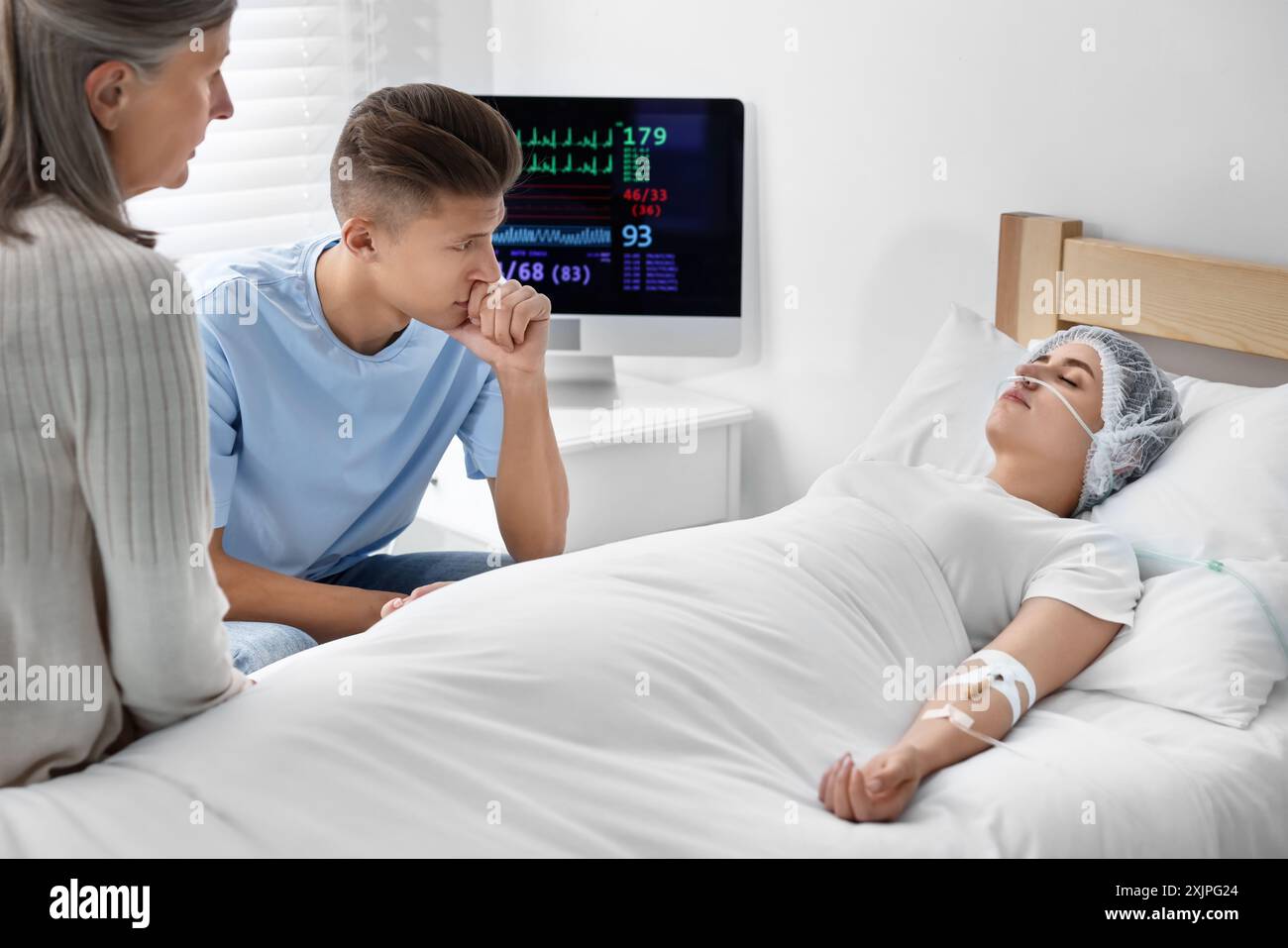 Coma patient. Sad relatives near sleeping young woman in hospital Stock ...