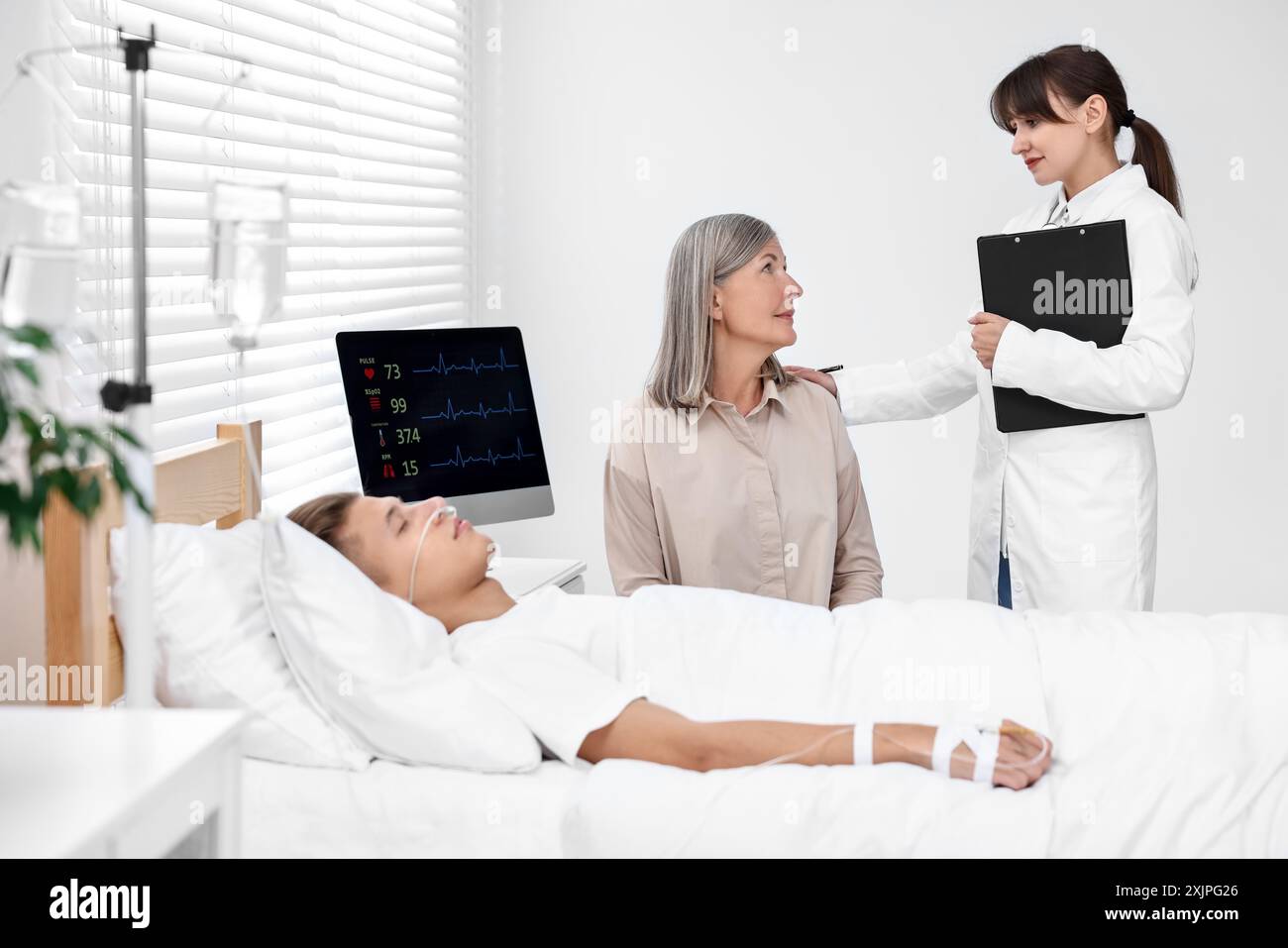 Coma patient. Sad mature woman near her unconscious son talking with ...