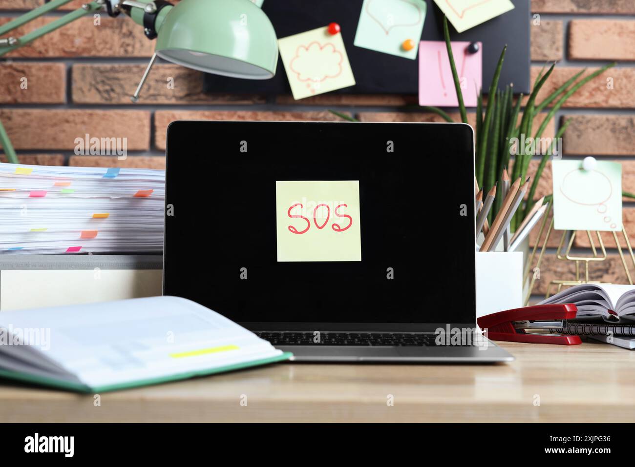 Sticky note with word SOS, laptop and stationery on wooden table at ...