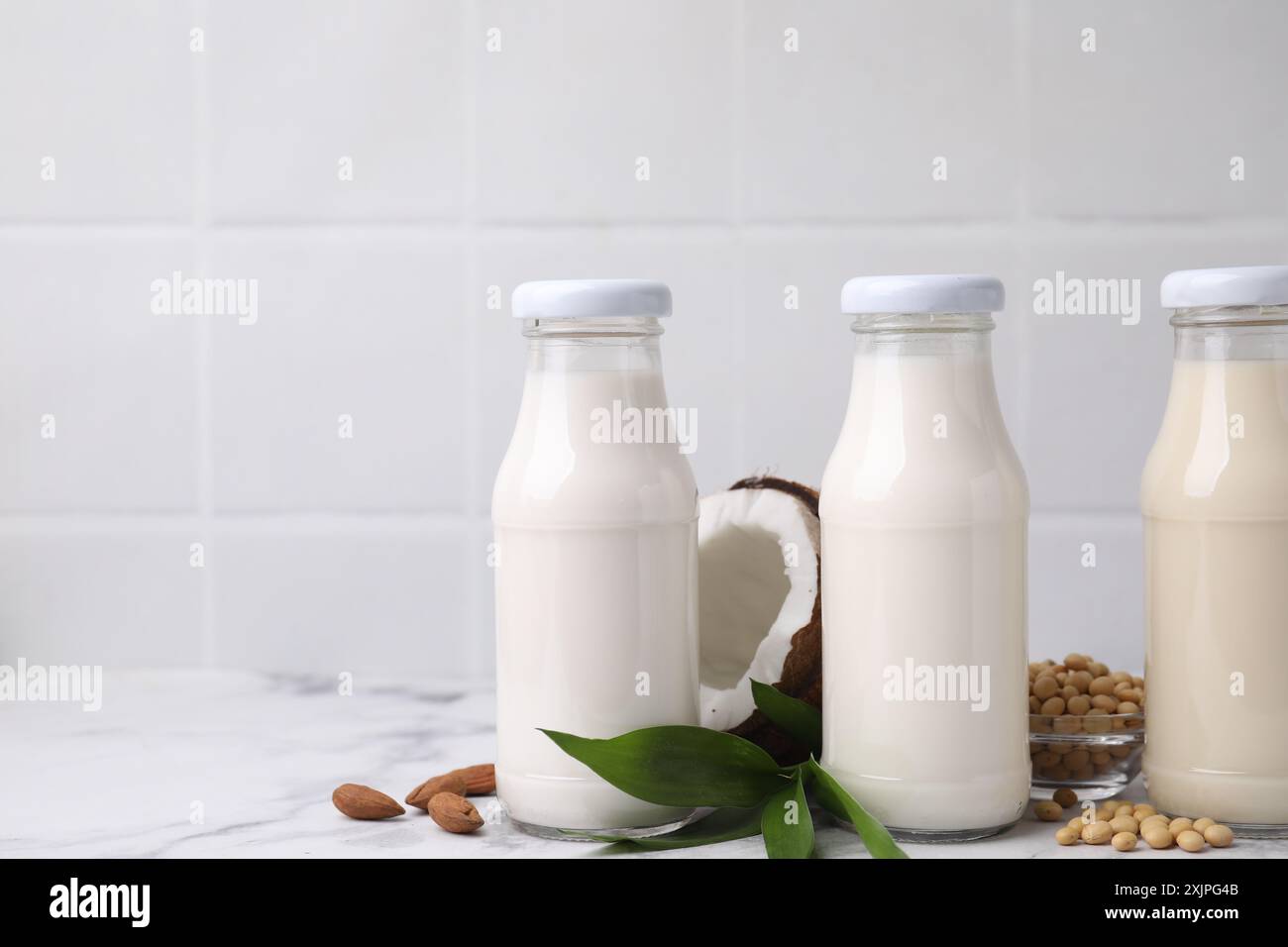 Different types of vegan milk in bottles with ingredients and green ...