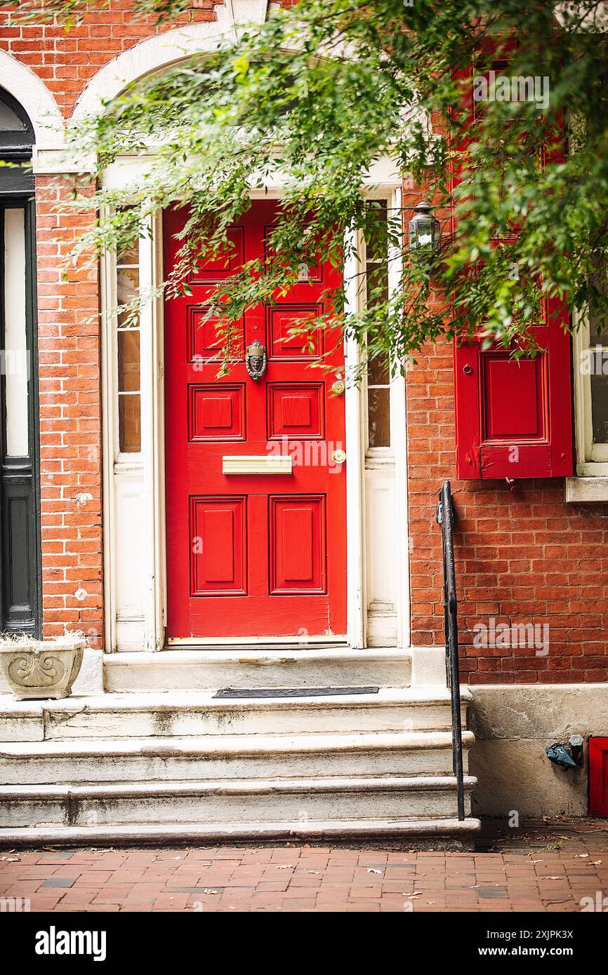 Beautiful red lacquered wooden door in a brick building and green tree ...