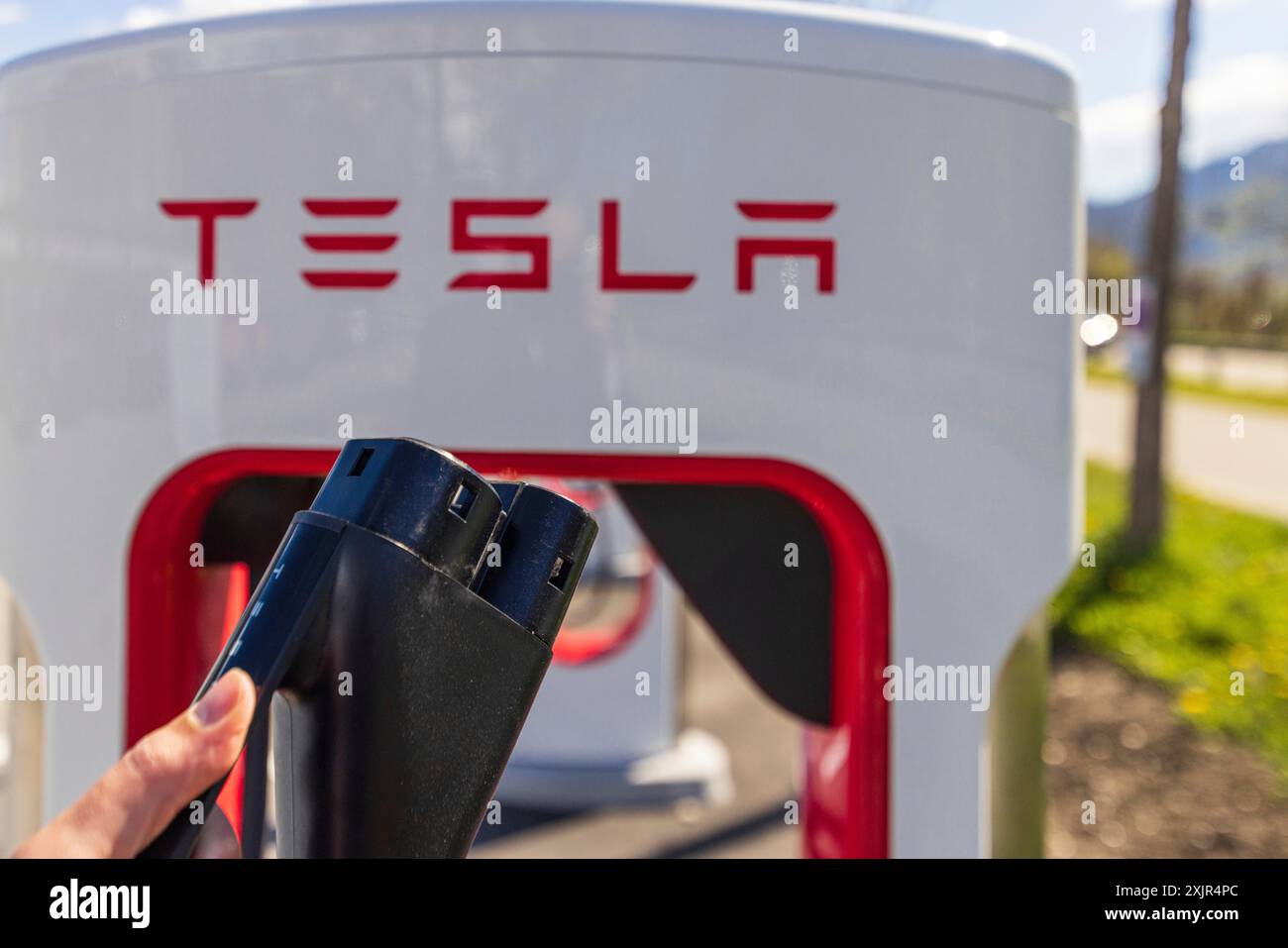 Tesla Superchargers on a parking lot, with a hand holding the CCS Type ...