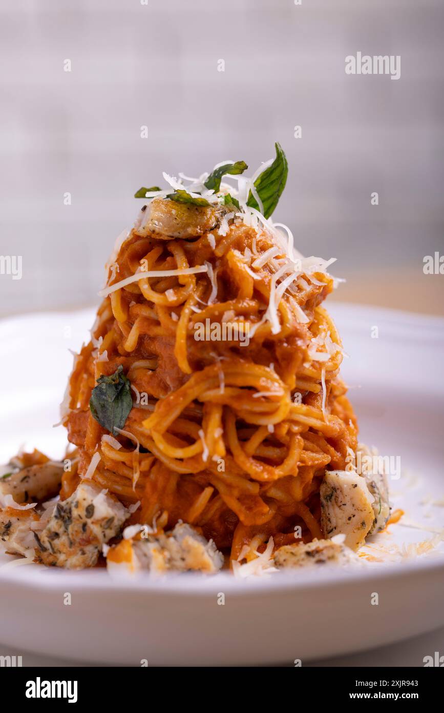 A beautifully plated tower of spaghetti coated in a rich tomato sauce ...