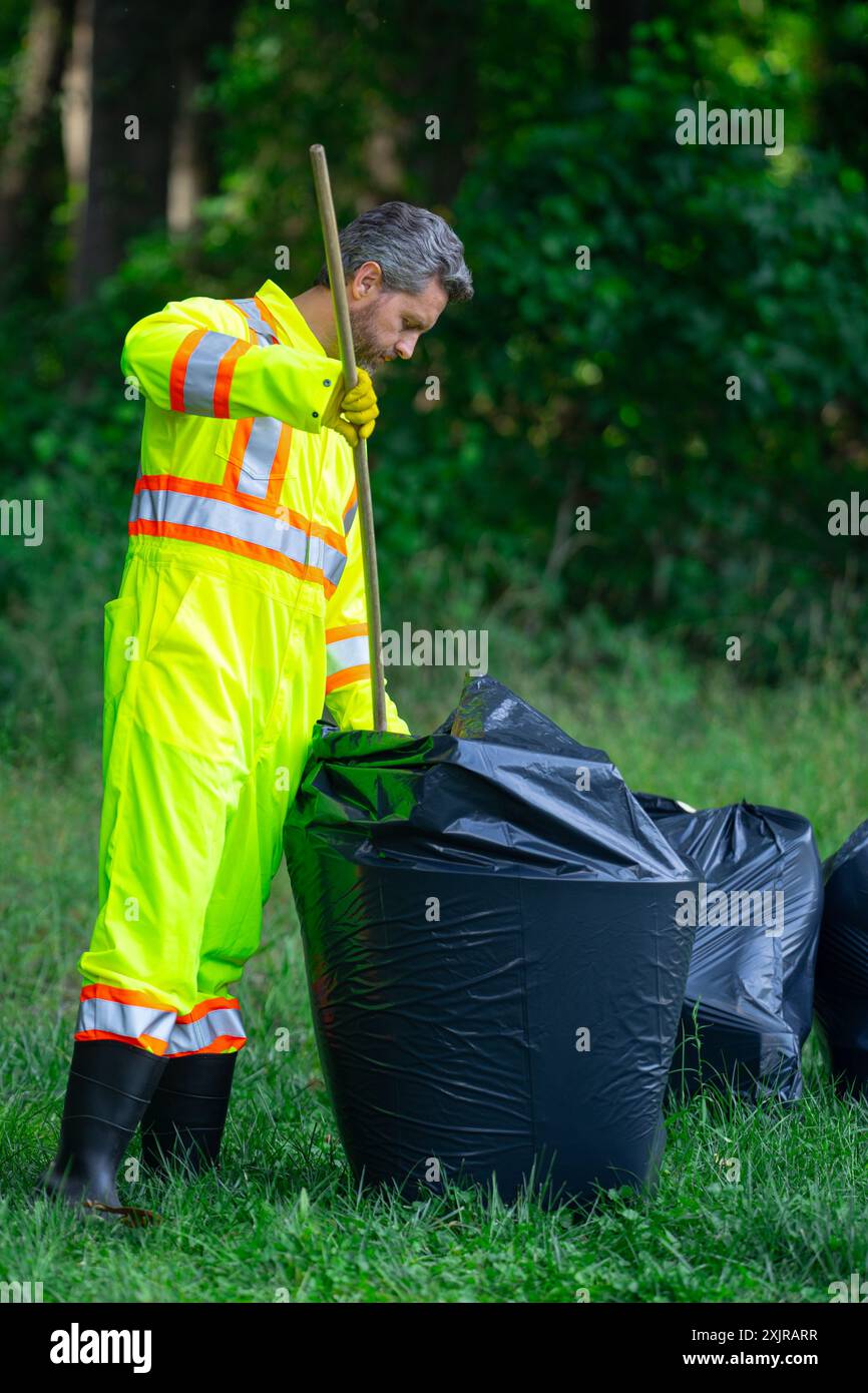 Environment plastic pollution. Volunteer collecting trash in the forest and holding a garbage ...
