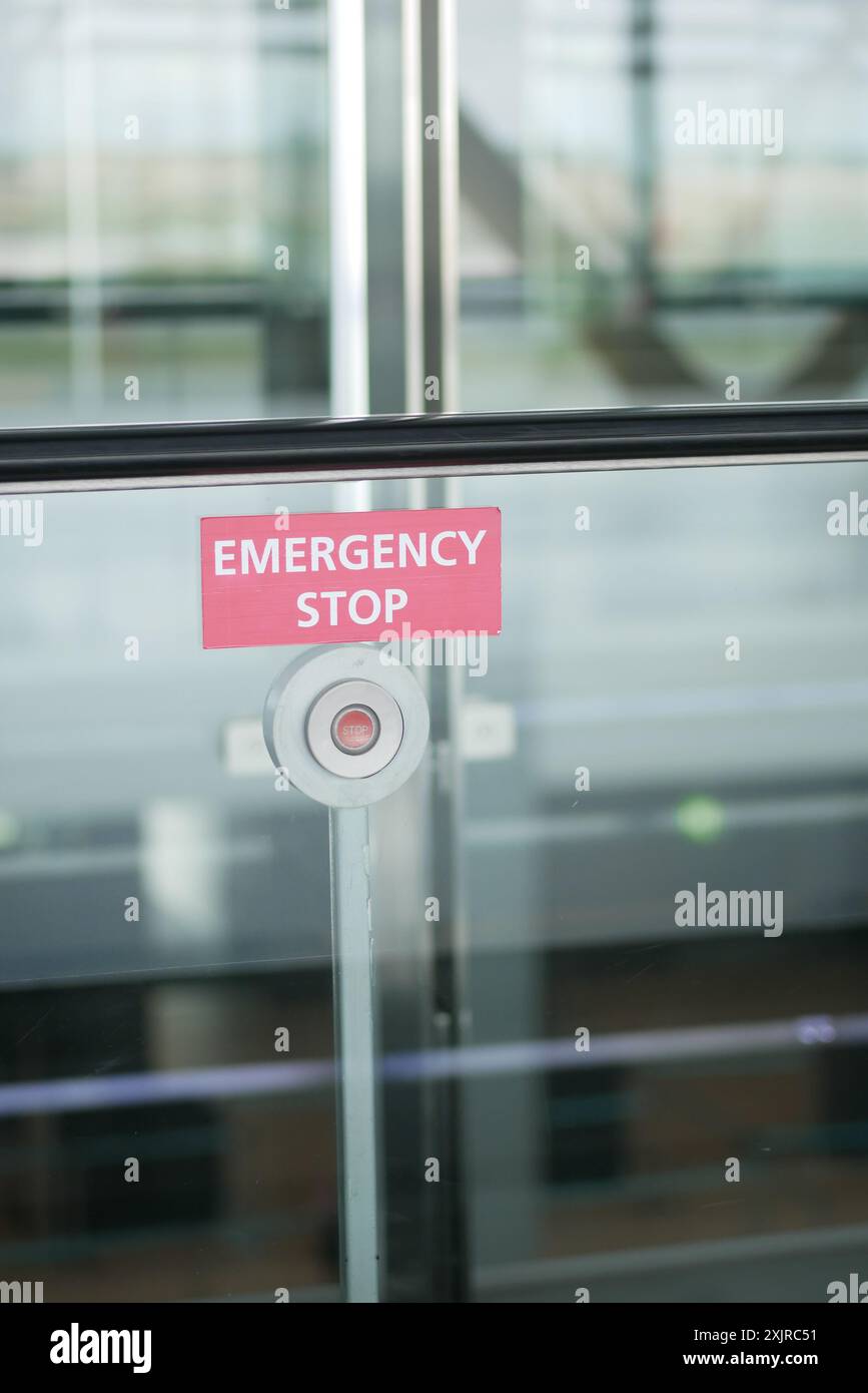 An emergency stop button is placed on a glass wall in a public space ...