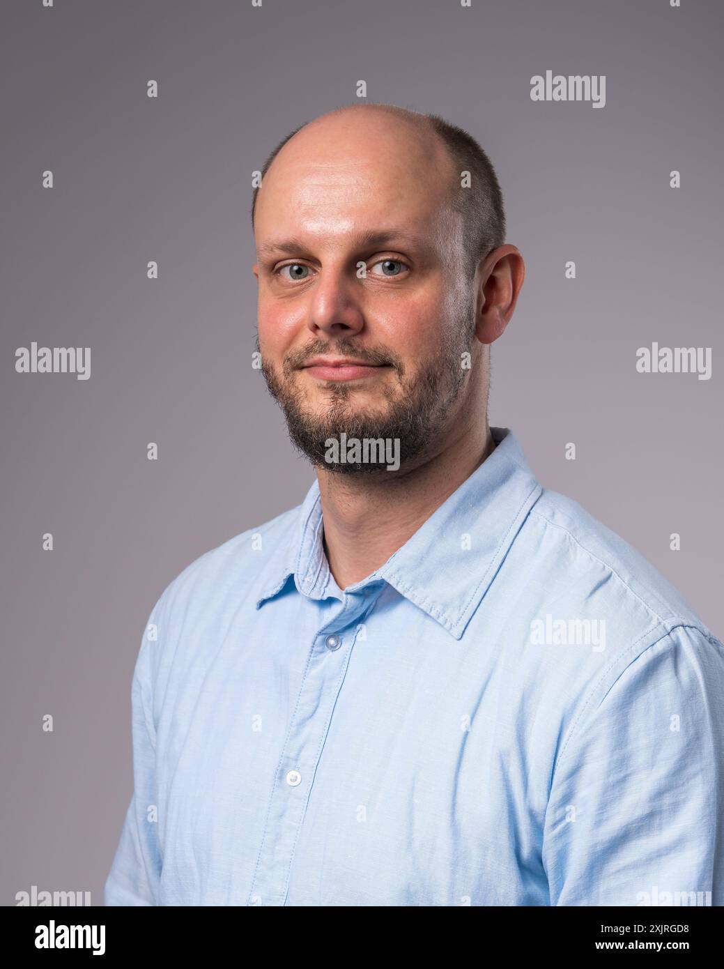 Portrait of a 35-year-old man with a beard in a blue shirt. Close-up ...