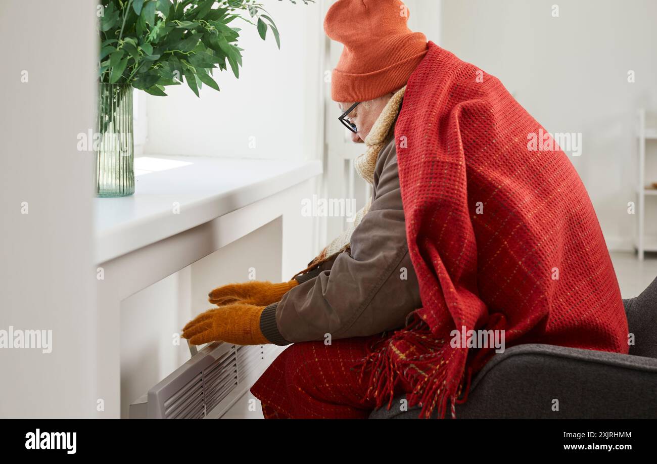 Senior Man Trying to Warm by the Heater in Living Room Stock Photo - Alamy