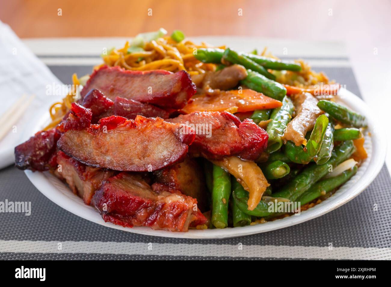 A closeup view of a combo dish, featuring BBQ pork, green beans, and ...