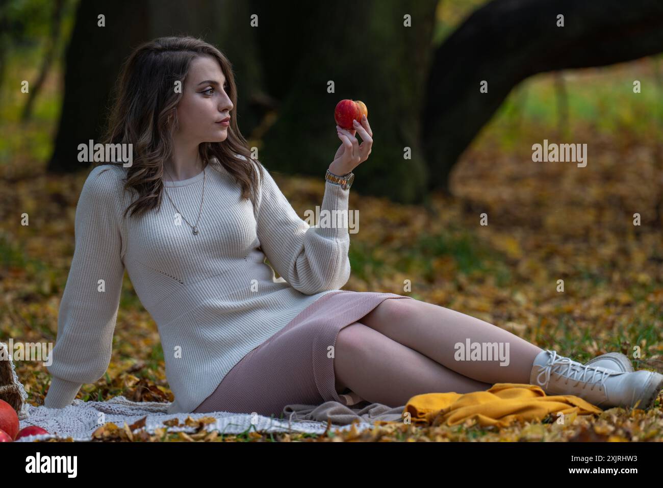 A beautiful girl with dark hair holds an apple in her hand and looks at ...
