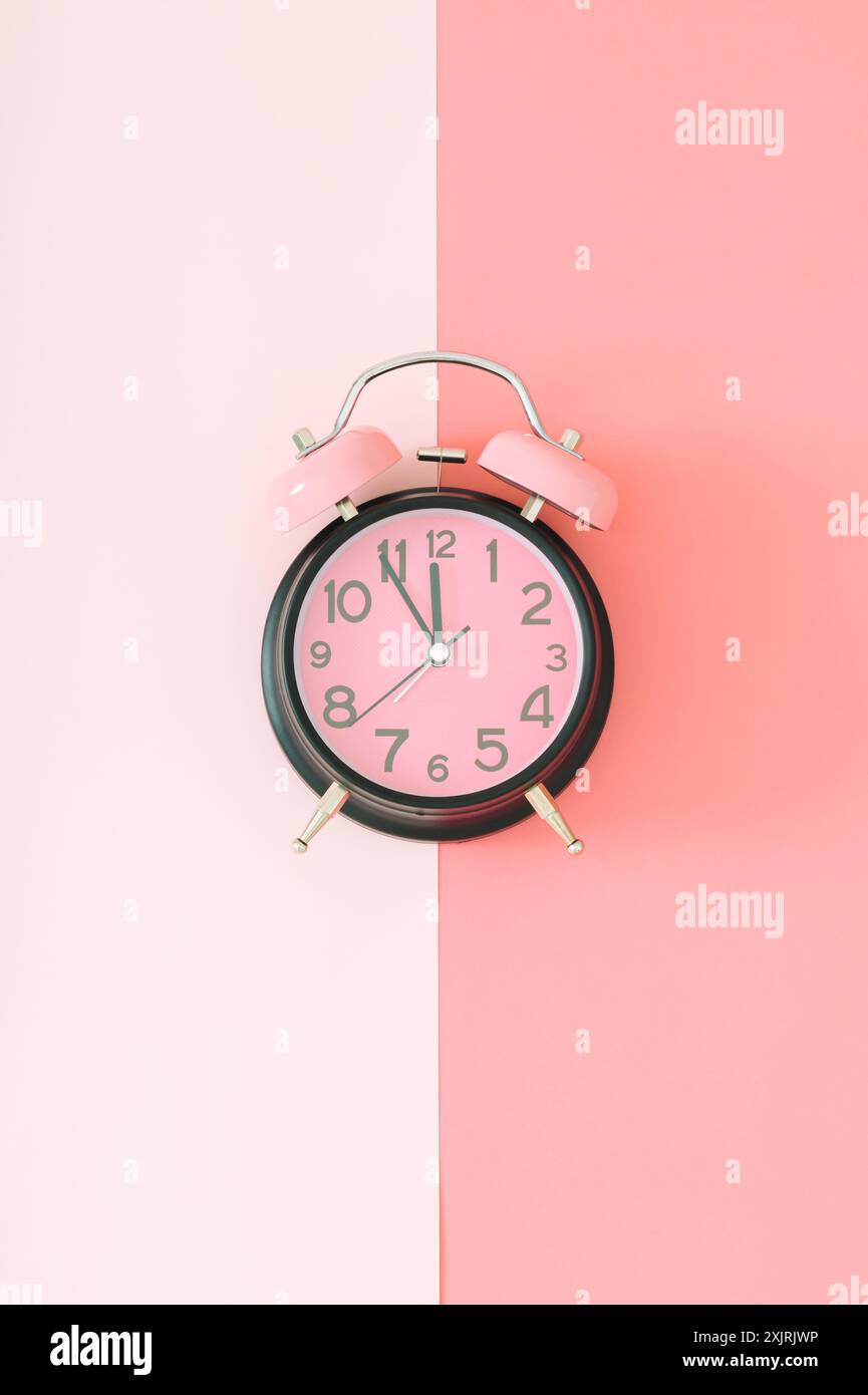 Pastel pink and black alarm clock on light and dark pastel pink ...