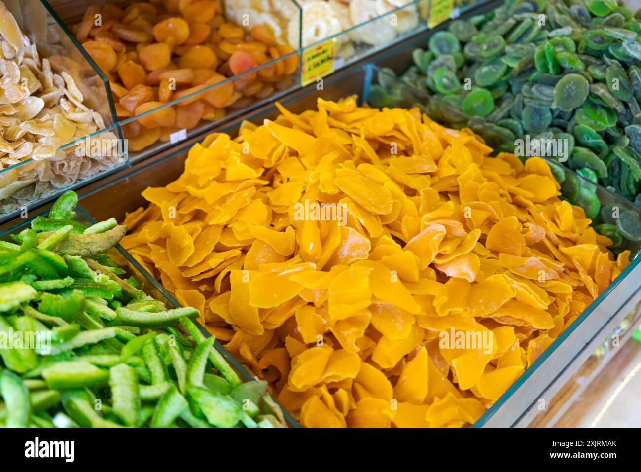 A variety of dried fruits in glass containers on display in a market ...