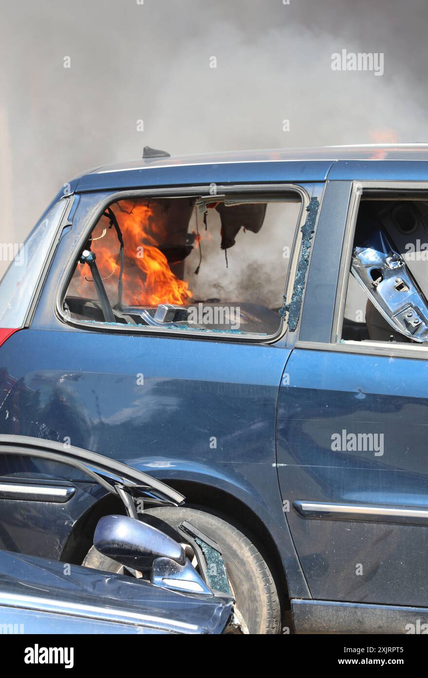 car with flames inside following a road accident leaving a door torn ...