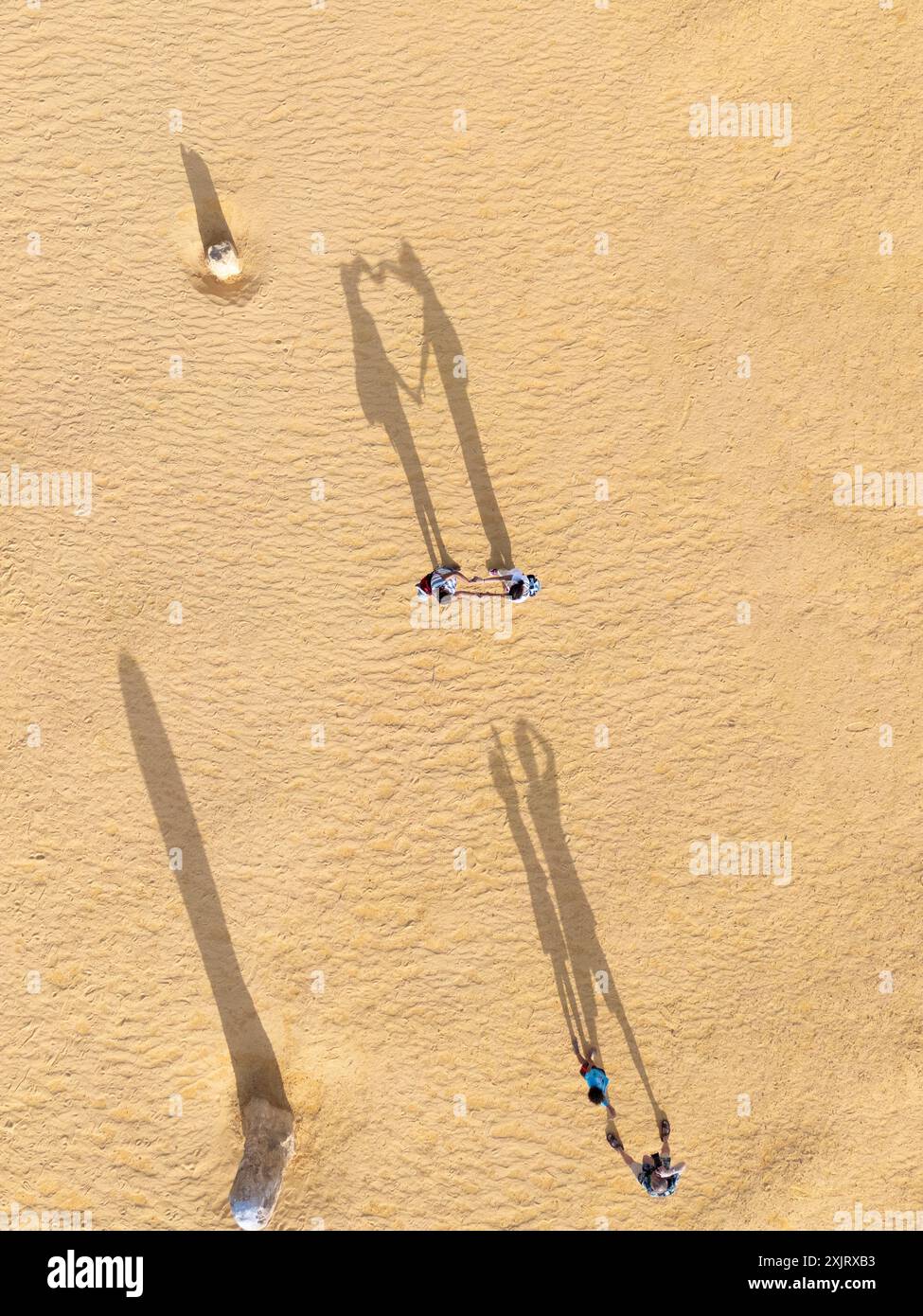 Aerial view of children playing around the pinnacles, casting long ...