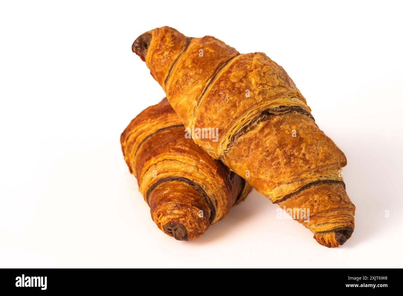 A two perfectly baked croissants, golden brown and flaky, are stacked ...