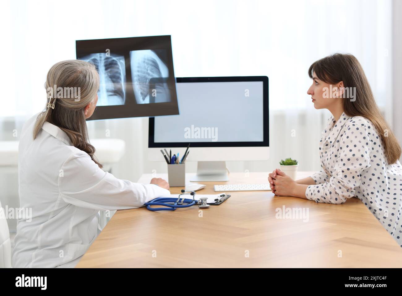 Lung disease. Doctor showing chest x-ray to her patient in clinic Stock ...