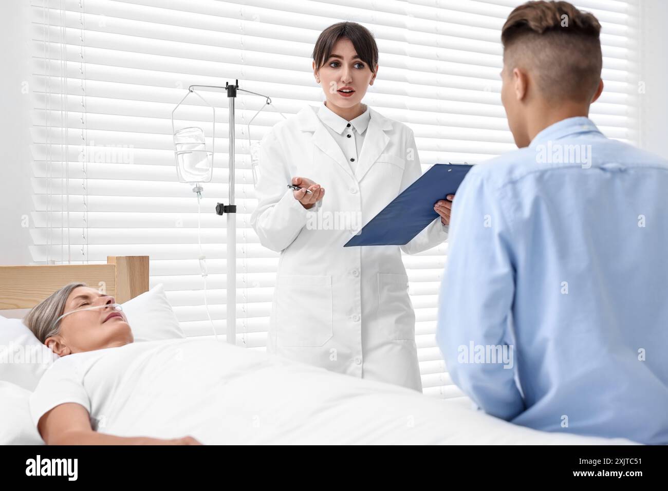 Coma patient. Sad young man near his unconscious mother talking with ...
