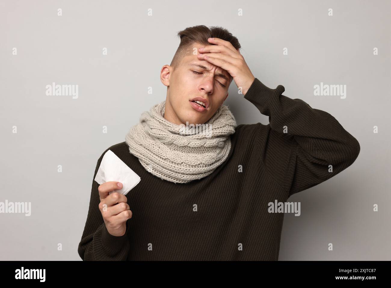 Sick man with tissue suffering from cold symptoms on light grey ...
