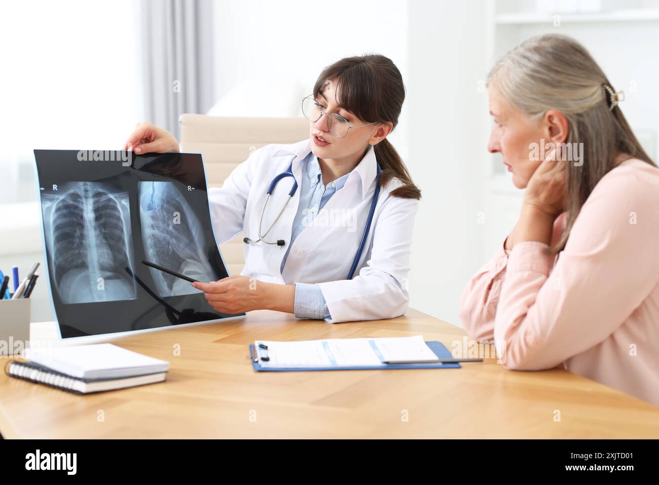 Lung disease. Doctor showing chest x-ray to her patient at table in ...