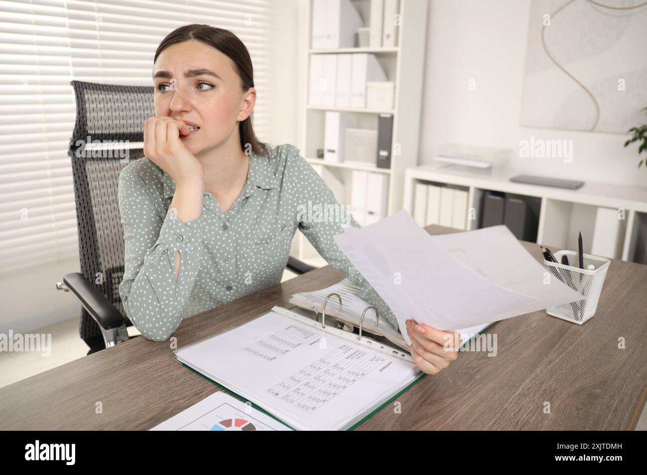Embarrassed woman with documents at wooden table in office Stock Photo ...