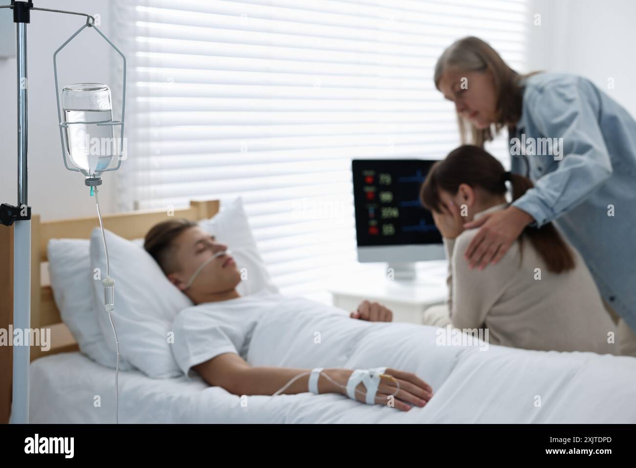 Coma patient. Sad women near unconscious young man in hospital Stock ...