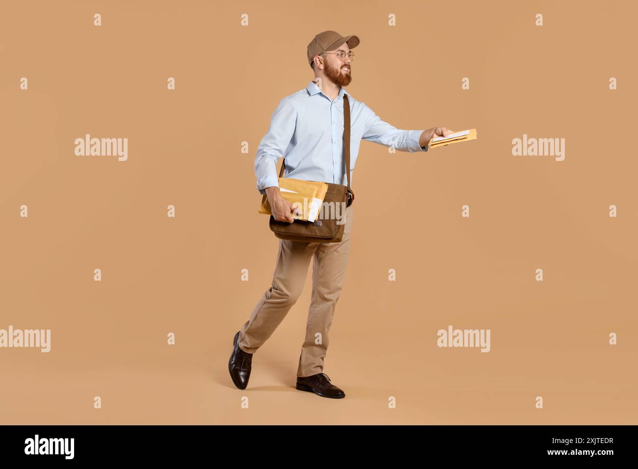 Happy young postman with leather bag delivering letters on brown ...