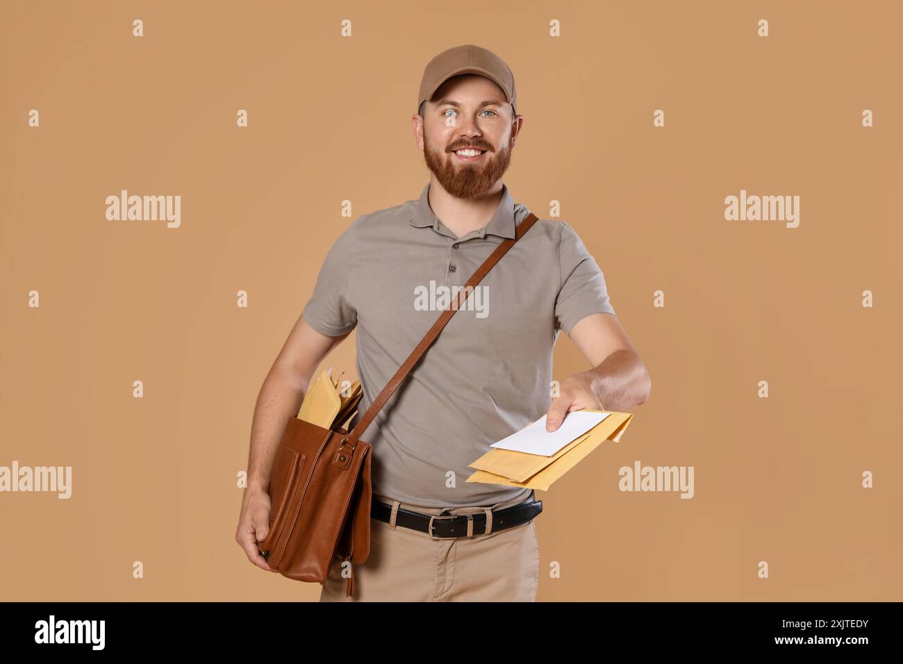 Happy young postman with leather bag delivering letters on brown ...