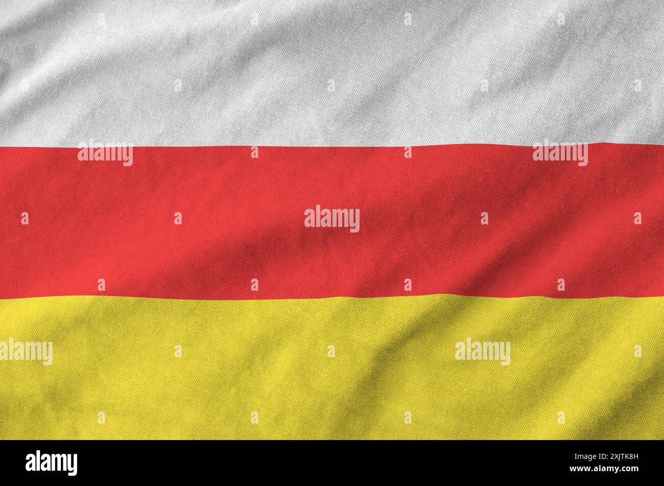 South Ossetia flag depicted on folded wavy fabric of old cloth close up ...