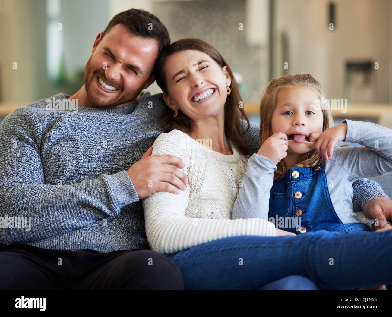 Parents, girl and happy on sofa with funny face at home for bonding ...