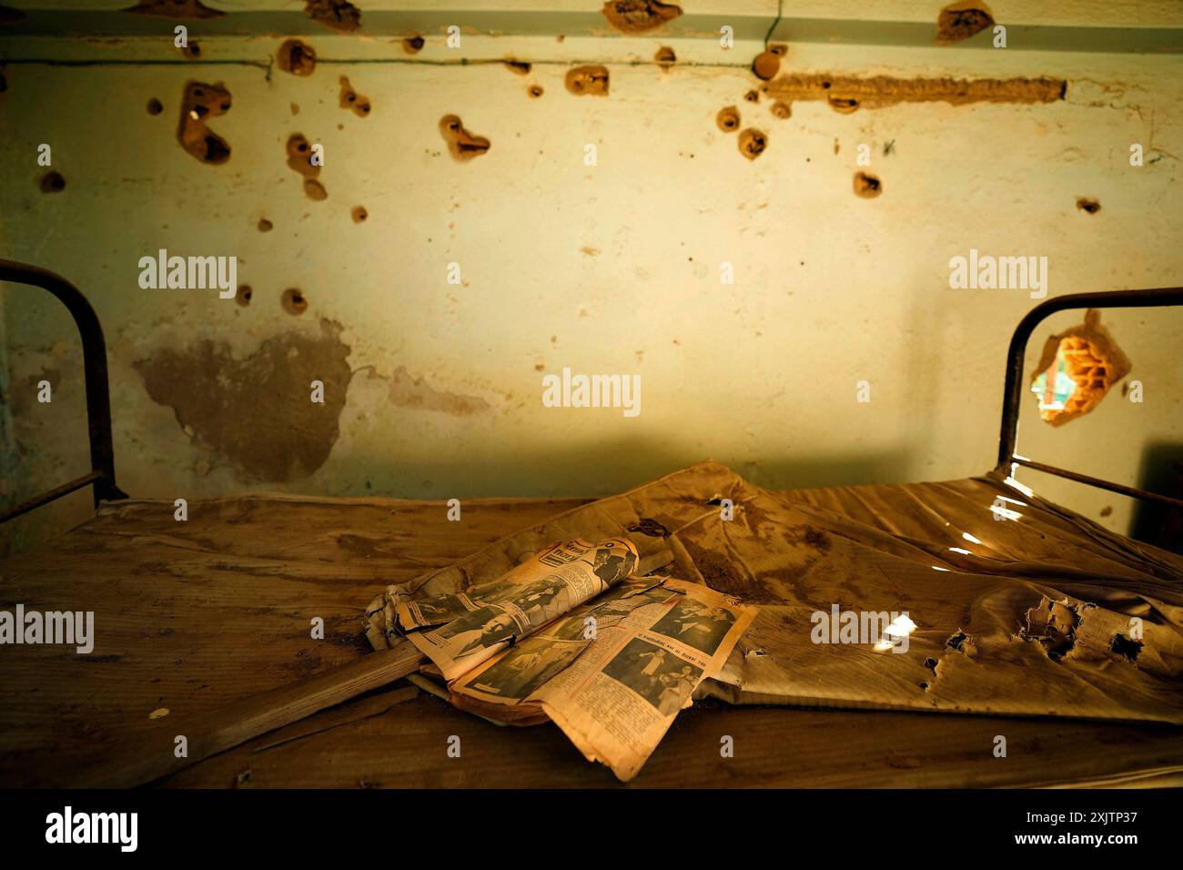 Holes from bullets are seen on a wall on top of a destroyed bed with a ...