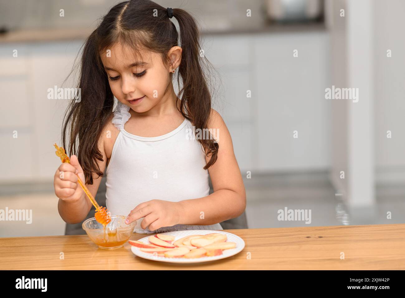 Little girl eating apple with honey. Symbol of the Jewish New Year Rosh ...