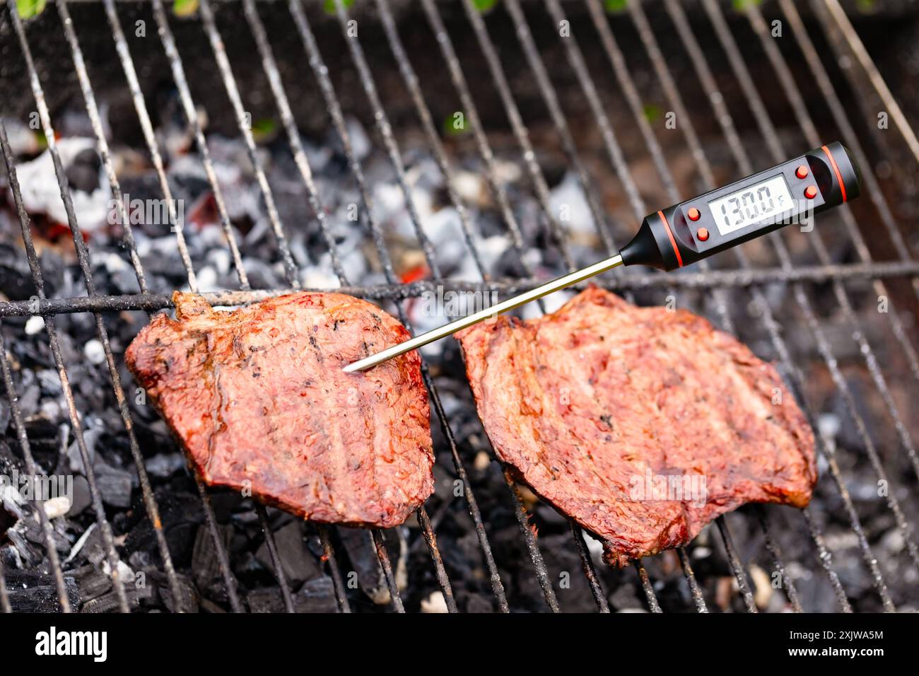 Grilled steak on barbecue with digital meat thermometer showing 130.0°F ...