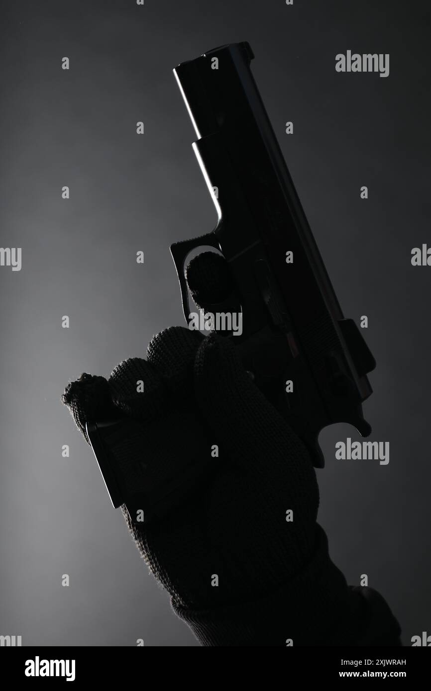 Dangerous criminal with gun on black background, closeup. Armed robbery ...