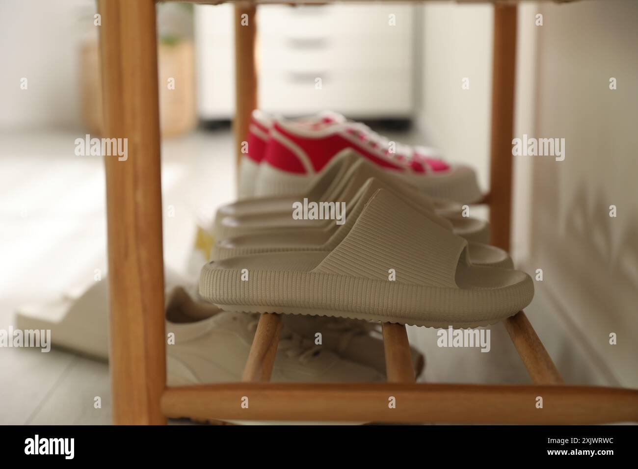 Pairs of slippers and sneakers on shoe rack at home Stock Photo - Alamy