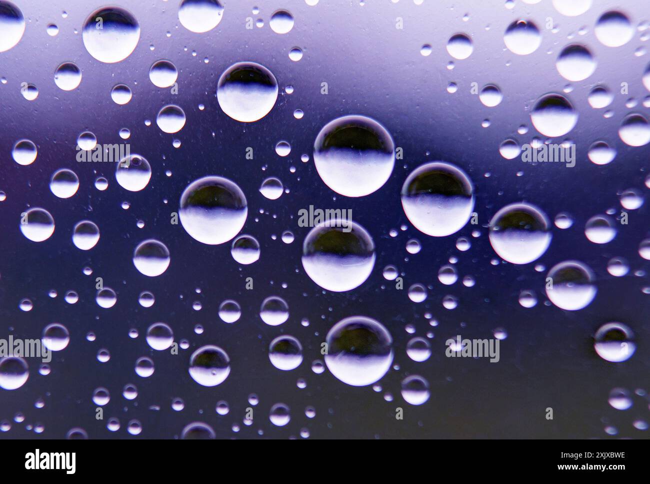Straight view of water droplets on clear glass on blurred nature background. Suitable for design ...