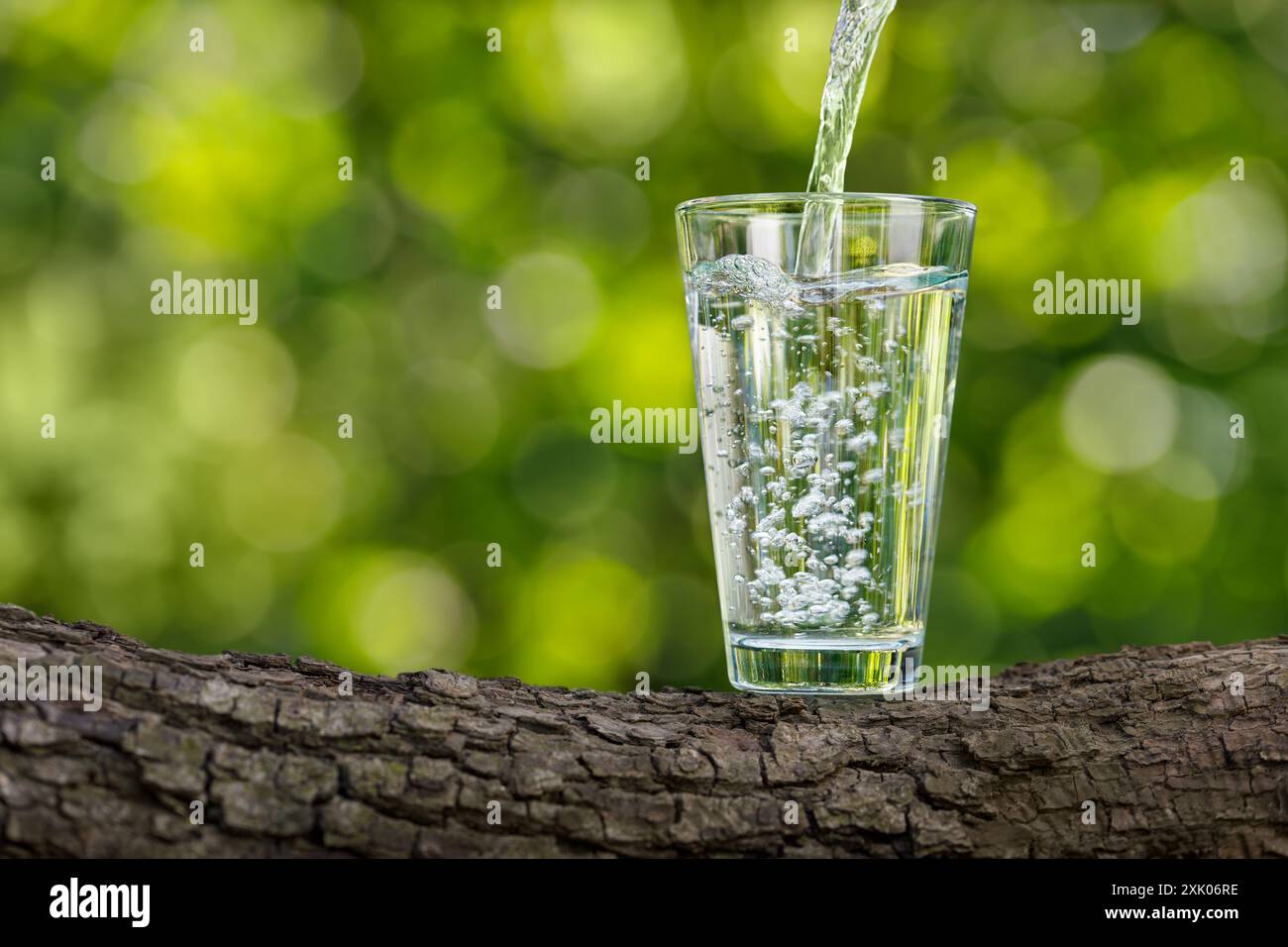 water pouring into glass on log with green natural background Stock ...