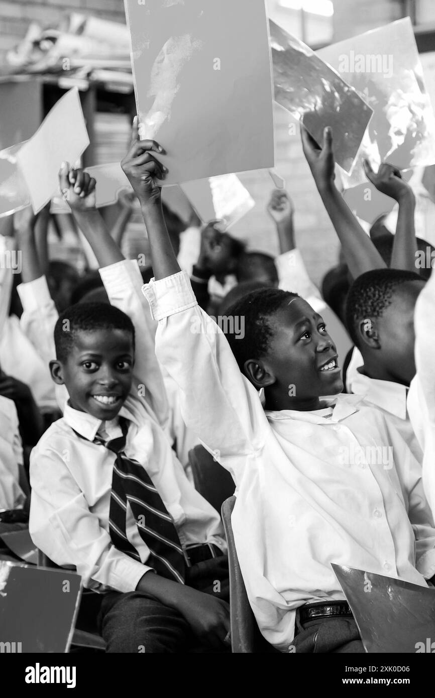 A black and white photo of African school children in uniforms raising their hands Stock Photo ...